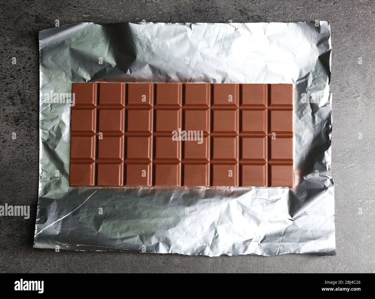 Chocolate bar in foil on gray background Stock Photo - Alamy
