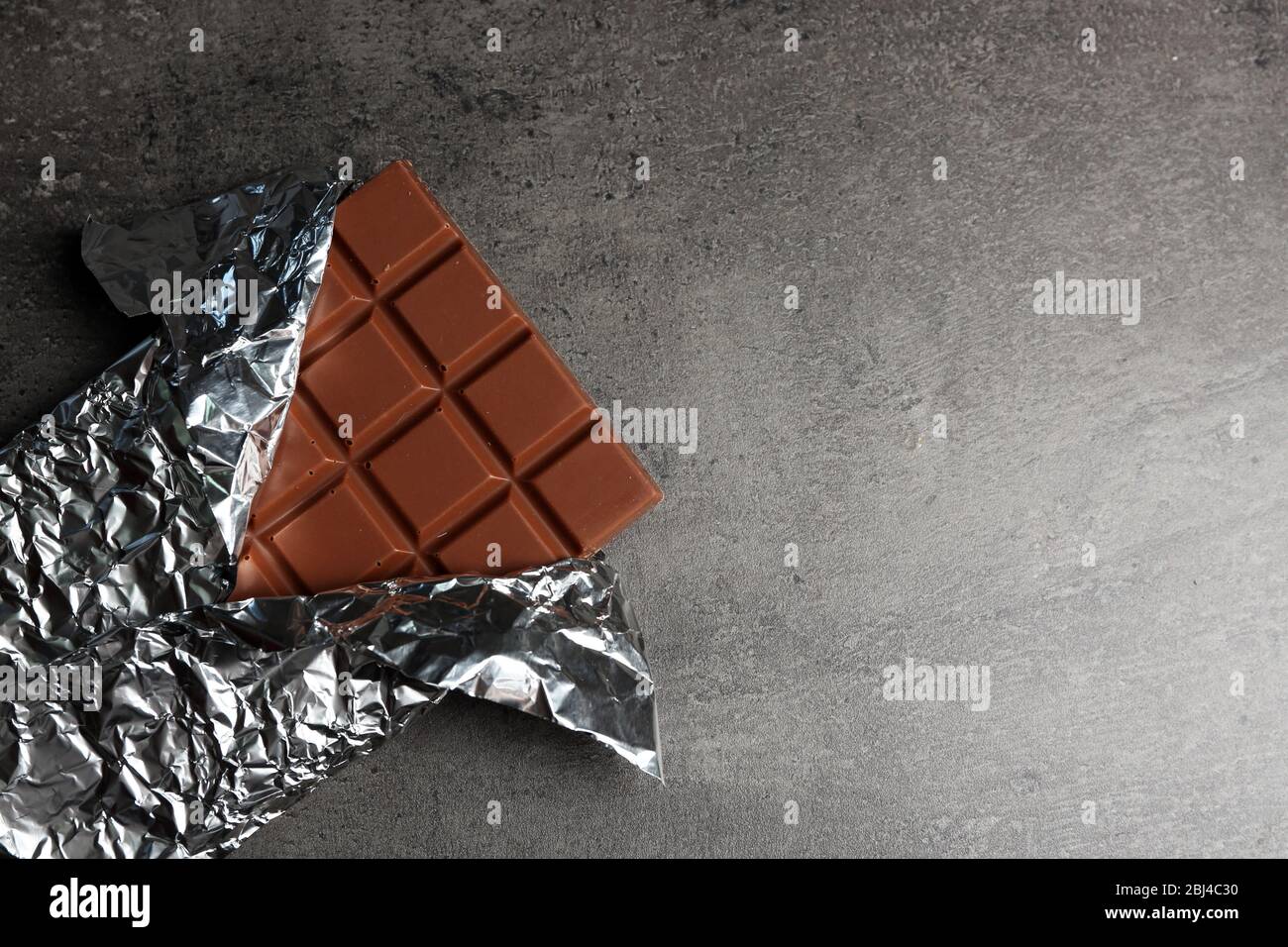 Chocolate bar in foil on gray background Stock Photo - Alamy