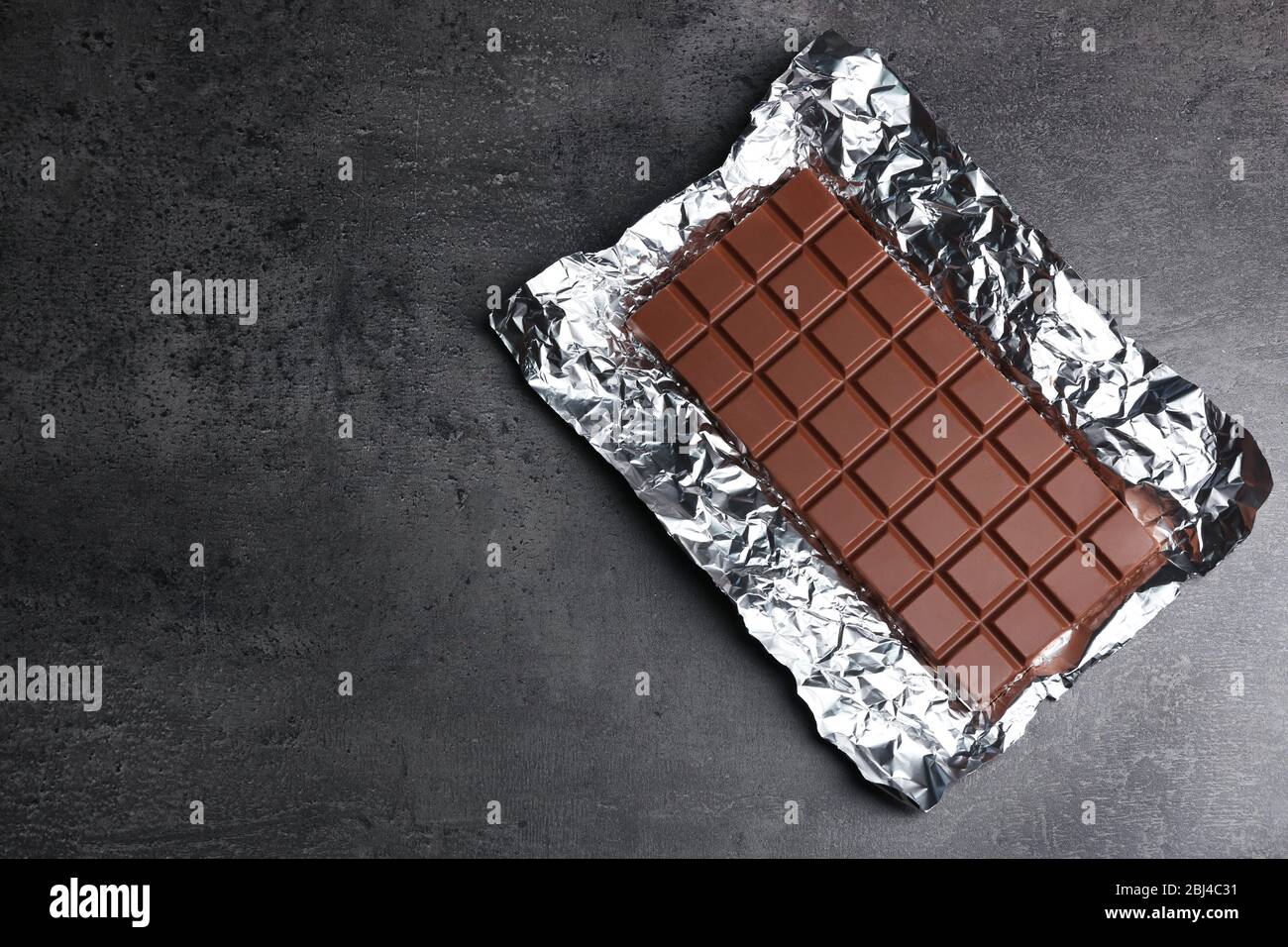 Chocolate bar in foil on gray background Stock Photo - Alamy
