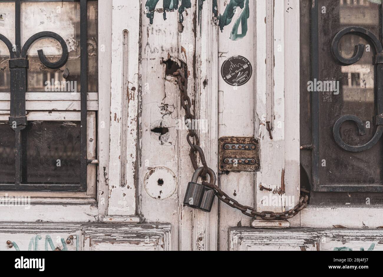 Architectural details of dirty white wooden door chained by old rusty ...