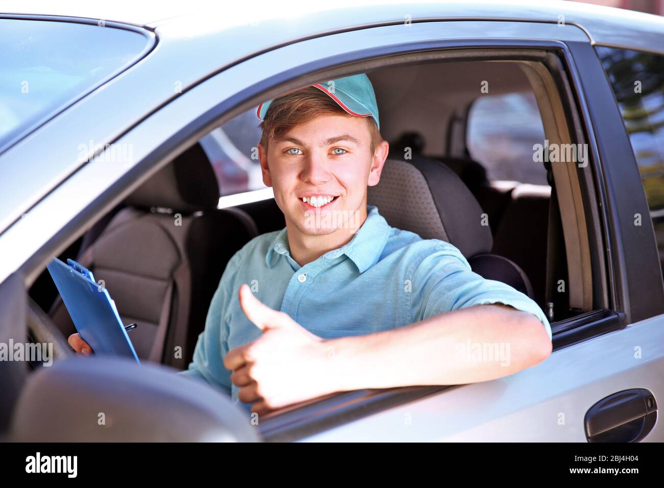 Pizza delivery boy with tablet in car, close-up Stock Photo - Alamy
