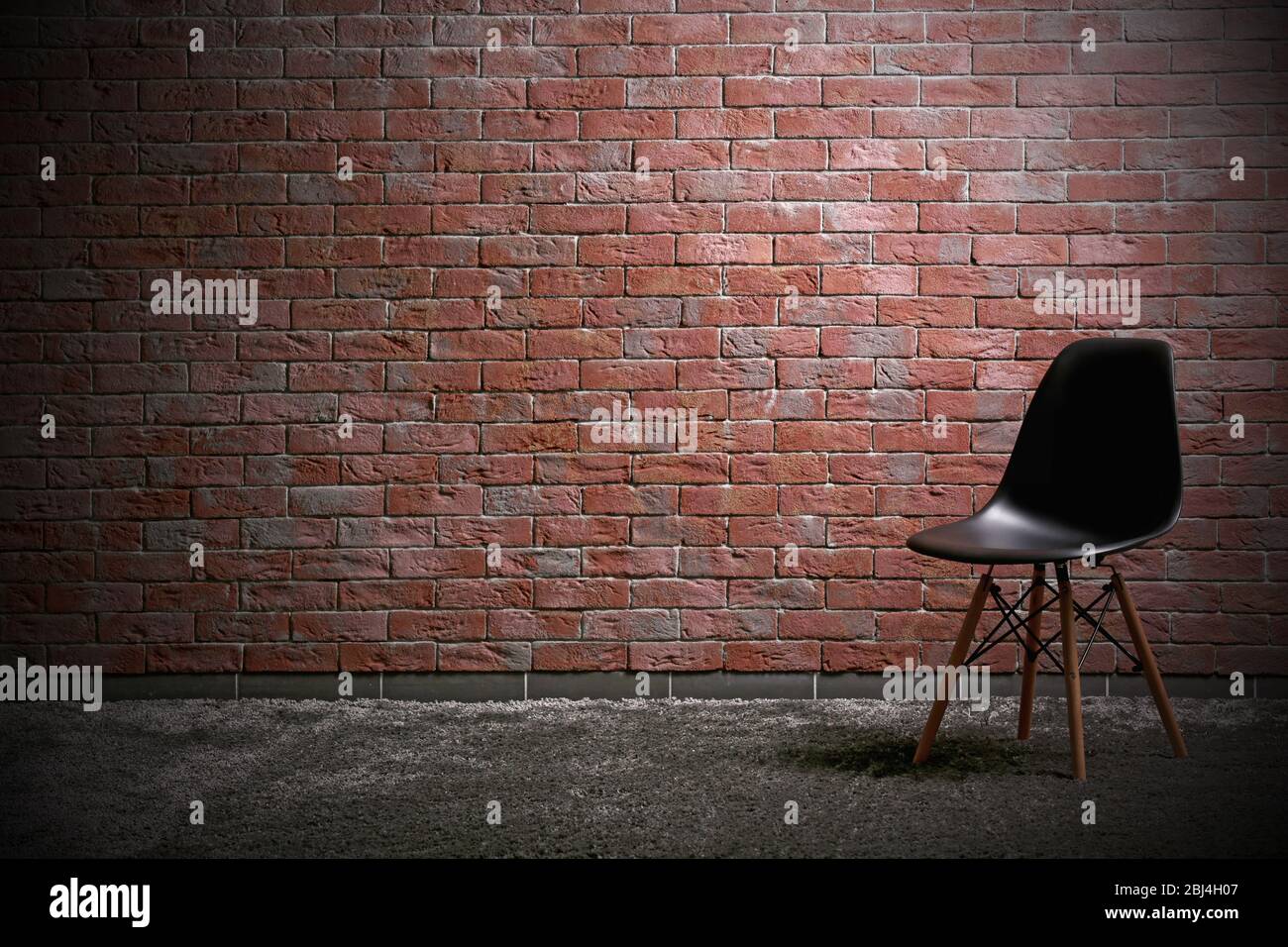 Black modern chair on red brick wall background Stock Photo - Alamy