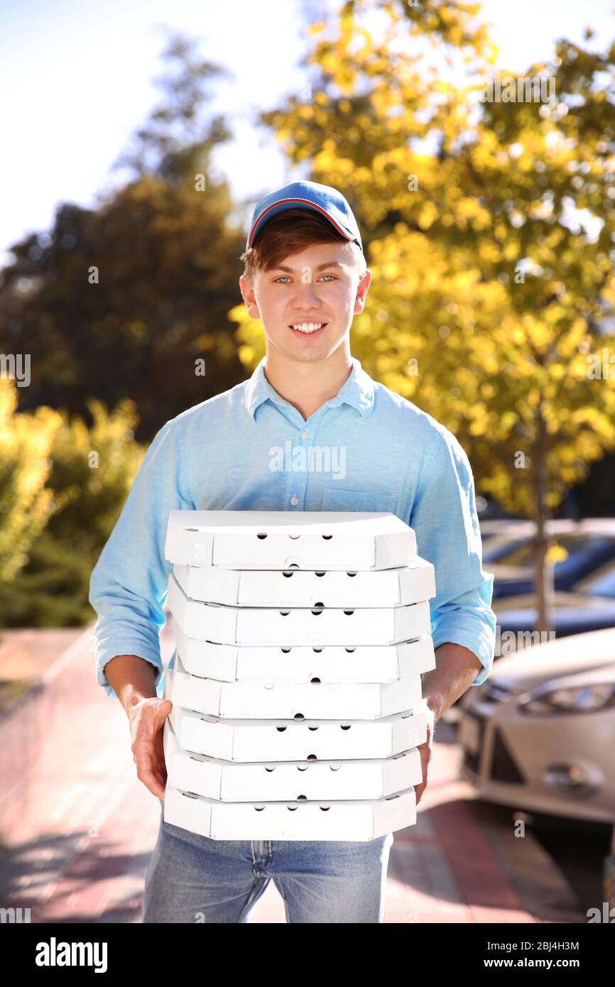Pizza delivery boy holding boxes with pizza, outdoors Stock Photo - Alamy