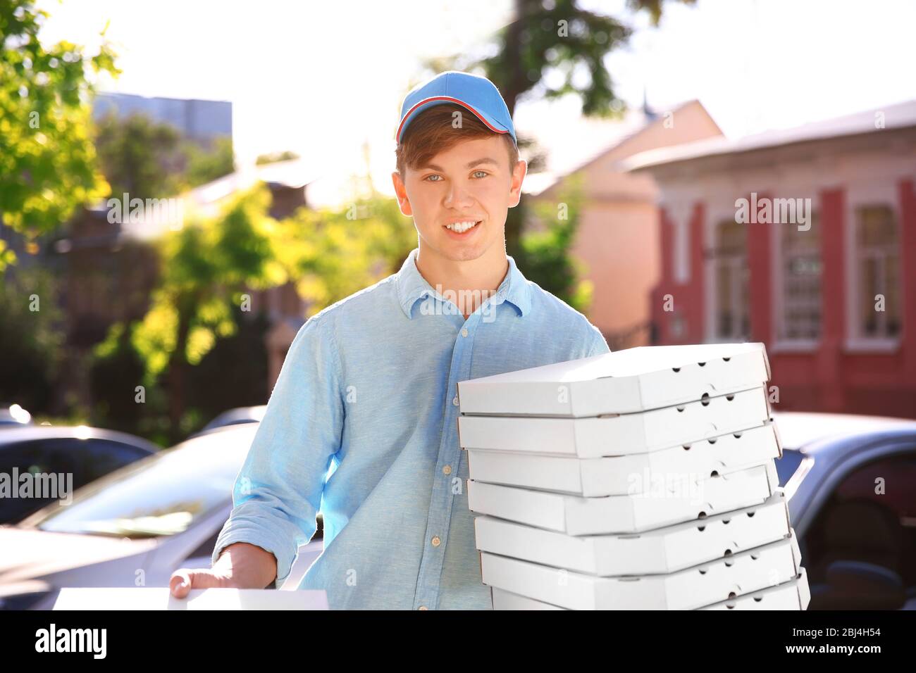 Pizza delivery boy holding boxes with pizza near car Stock Photo - Alamy