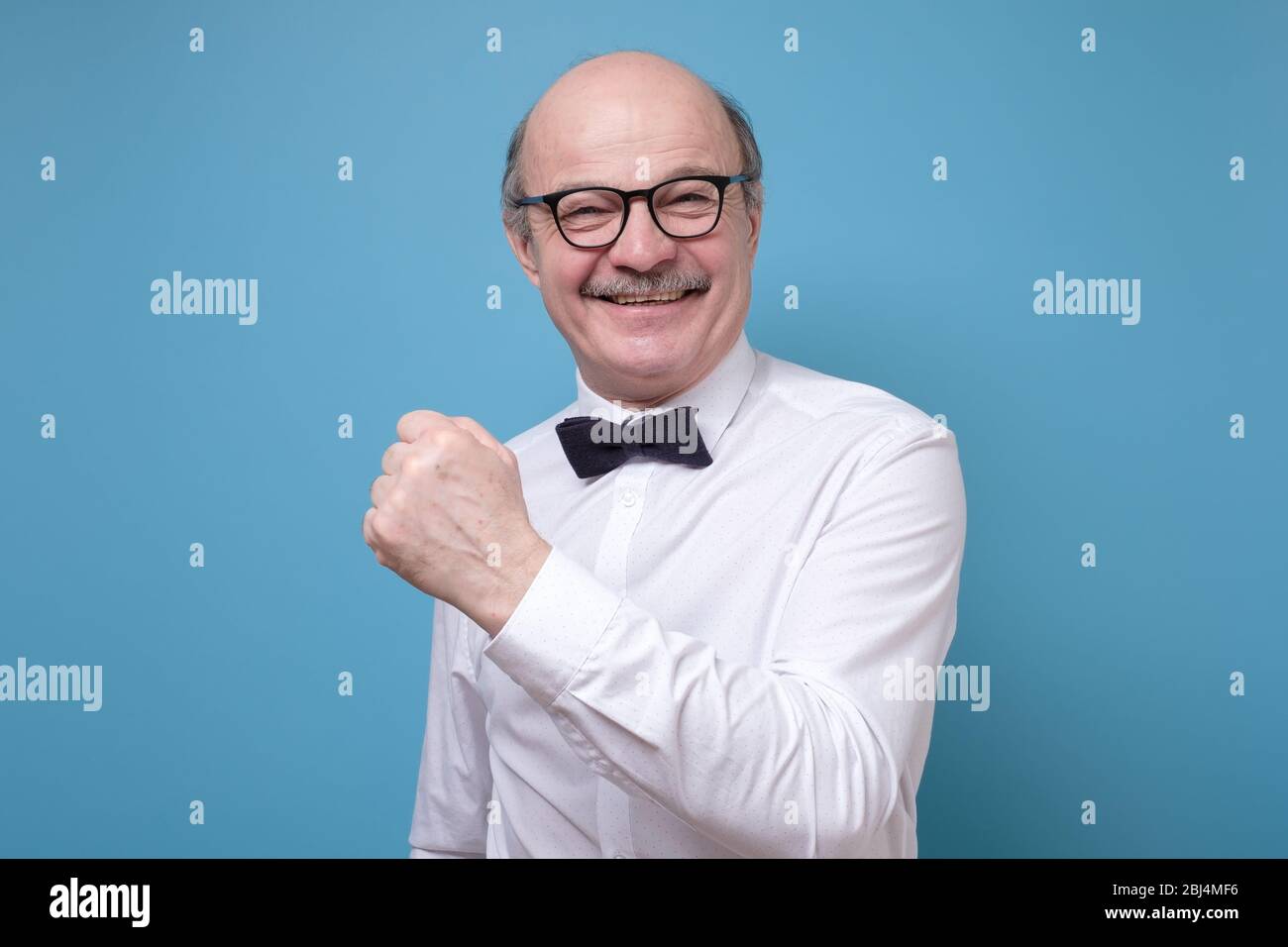 Senior hispanic man in glasses celebrating victory raising his fist ...