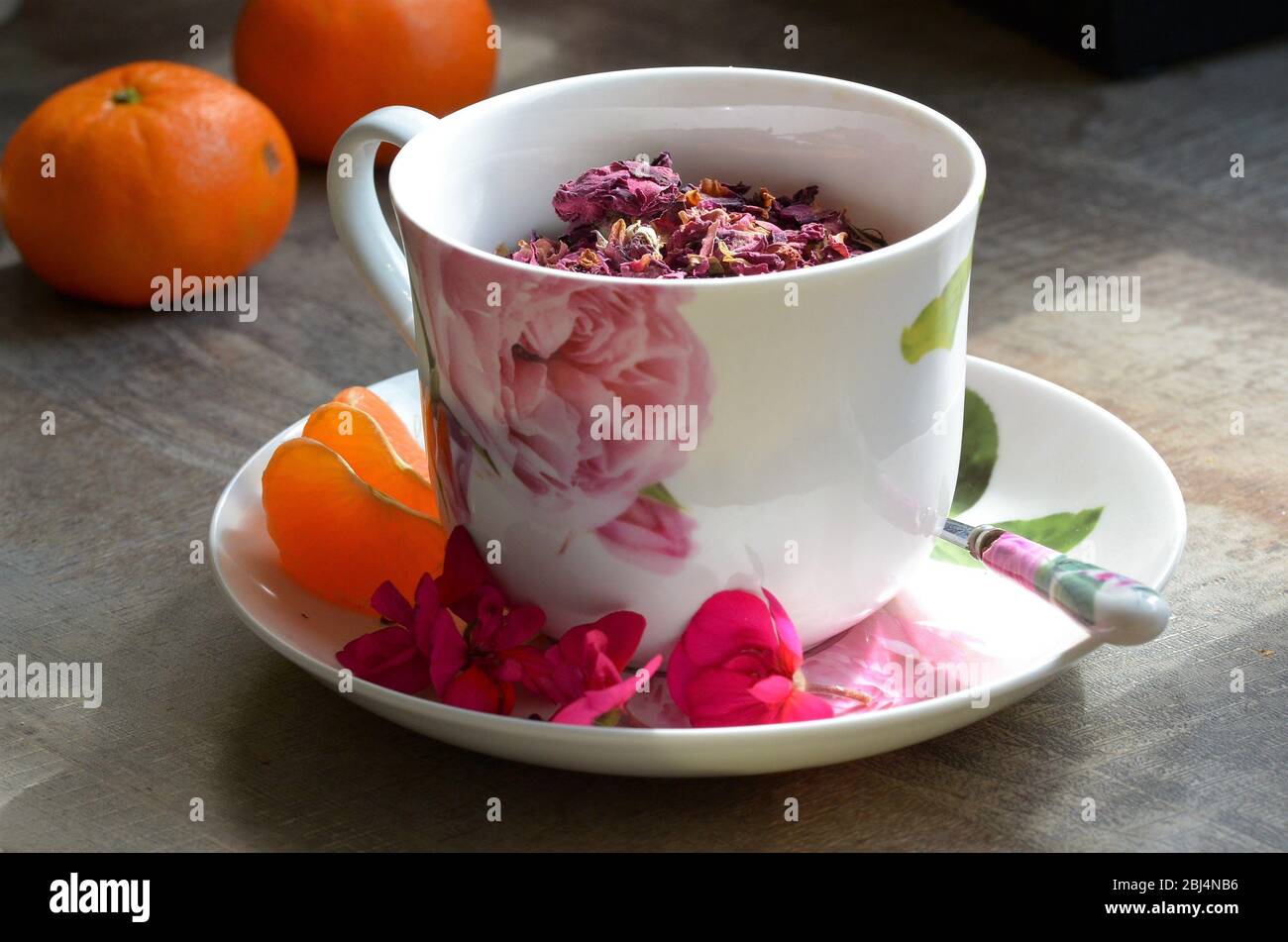 A romantic vintage tea cup with dried tea leaves and clementine slices ...