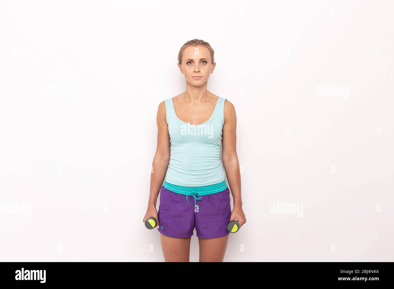 Lean woman in sport outfit with dumbells in hands on white isolated ...