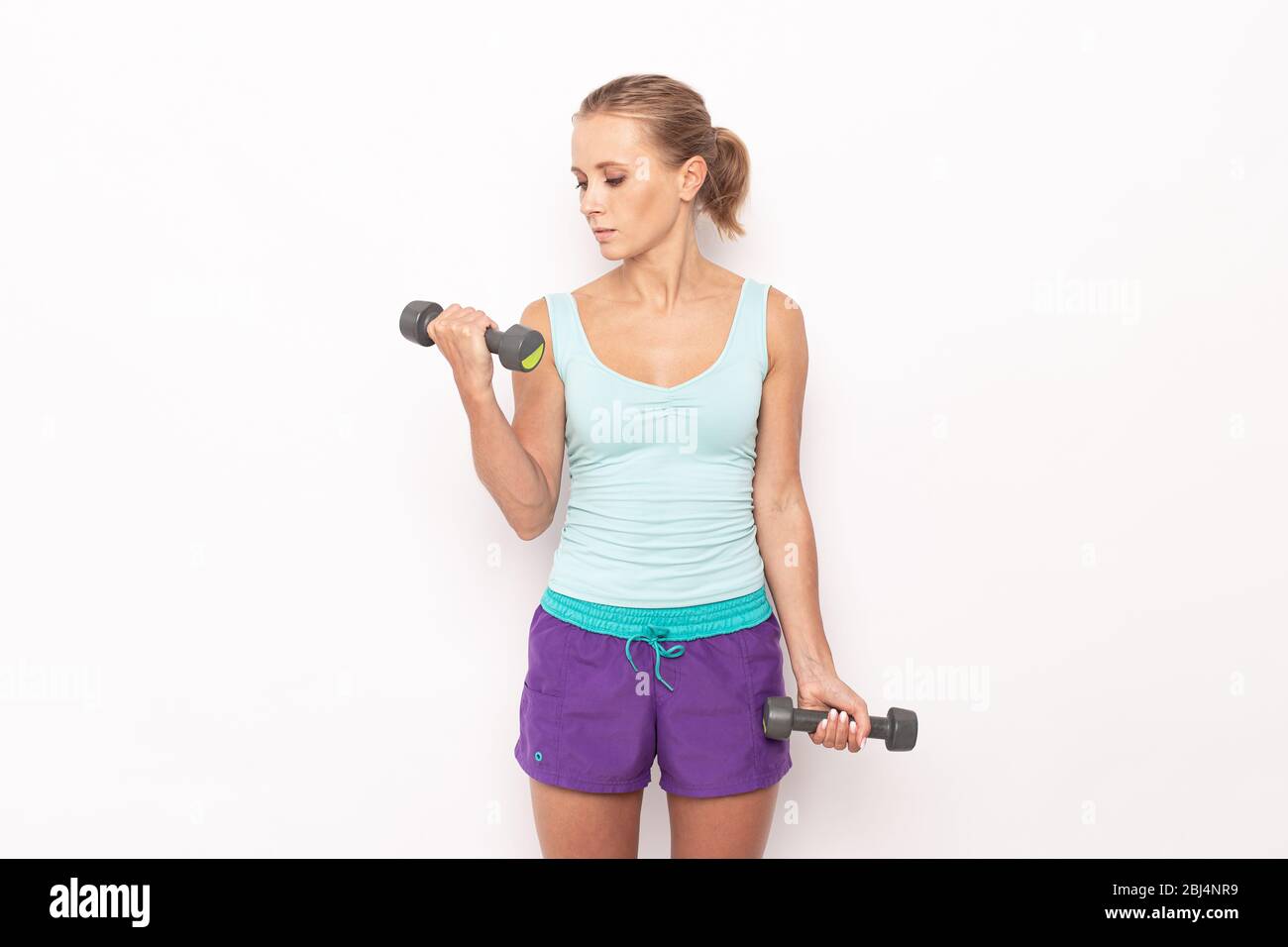 Sporty teen doing exercise with dumbbells in hands. White isolated ...