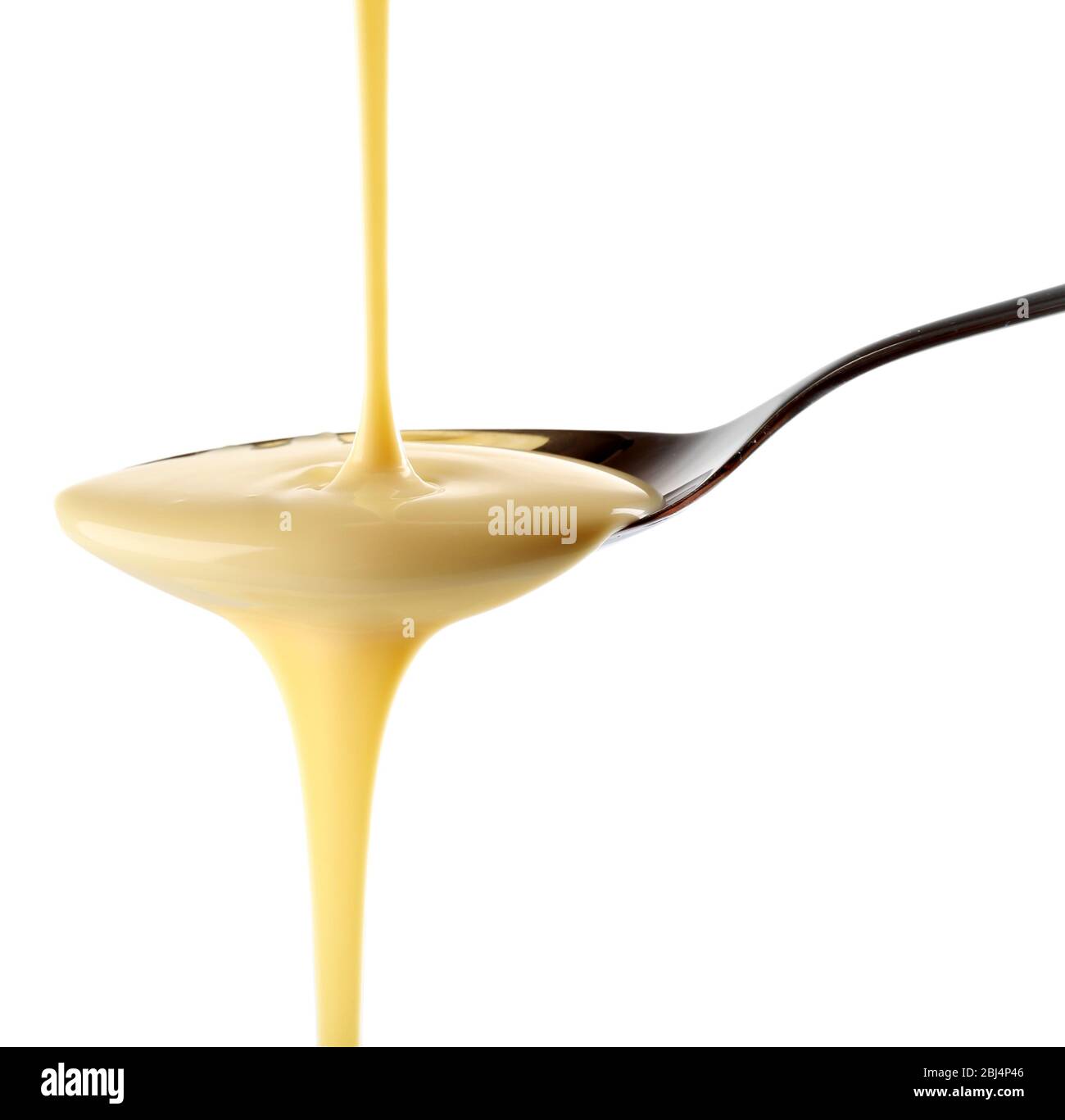 Condensed milk pouring from a spoon, isolated on white Stock Photo - Alamy
