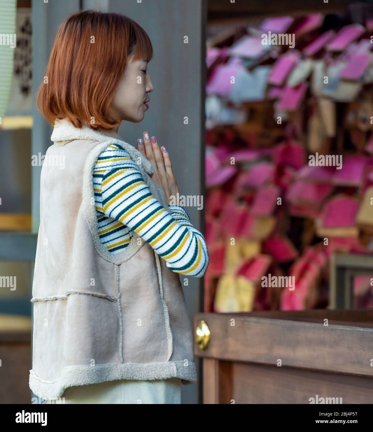 A Japanese woman praying at the Enoshima Shrine. Ema (wood prayer and ...