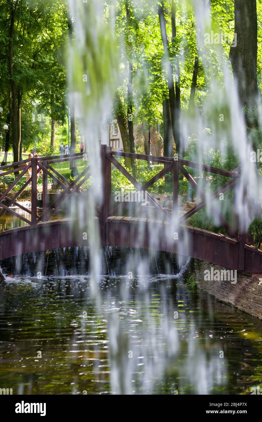 transparent falling water vertical flows against a blue sky and green ...