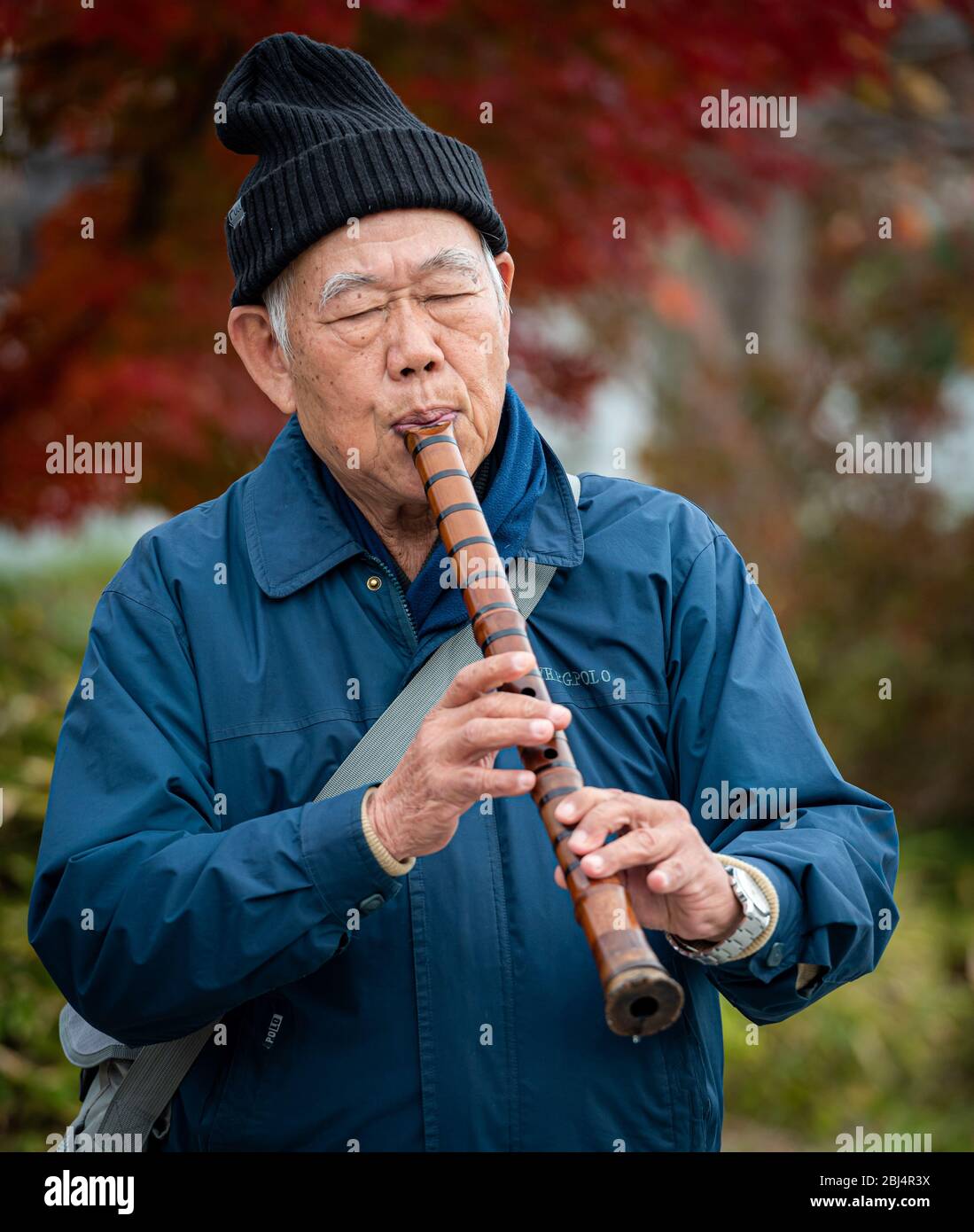 An elderly man plays the flute for tourists and visitors at the ...