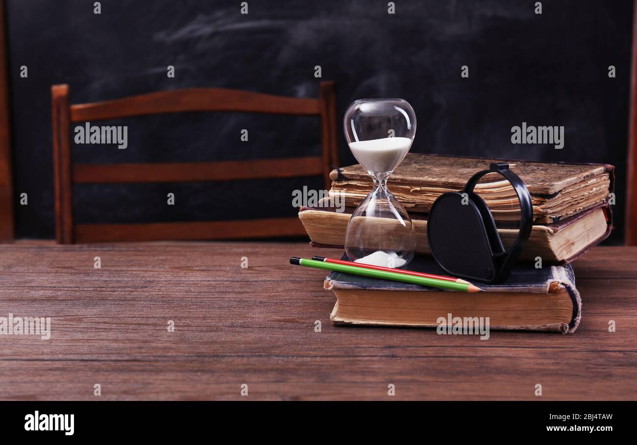 Books, hourglass and magnifier on wooden Stock Photo - Alamy