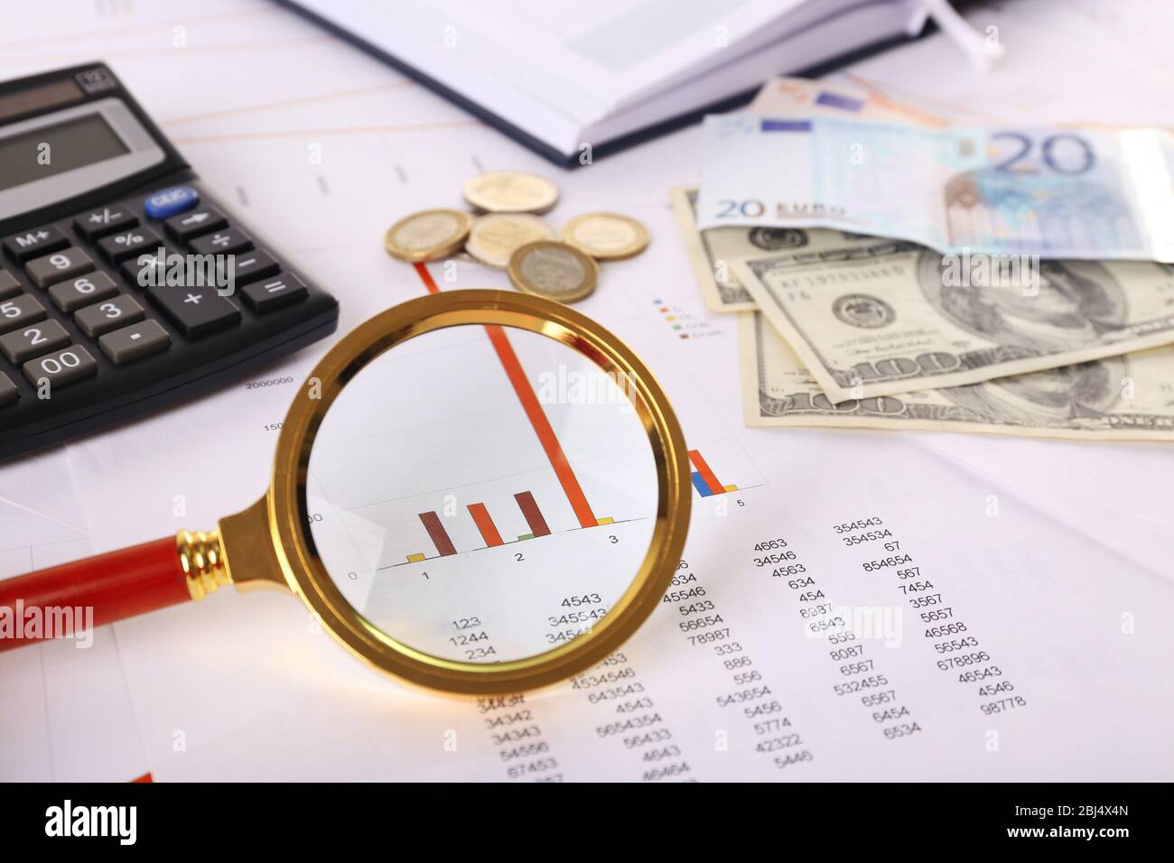 A magnifying glass on financial documents background, close-up Stock ...