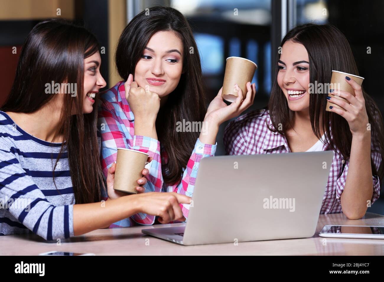 Best friends with laptop together sitting in cafe Stock Photo - Alamy