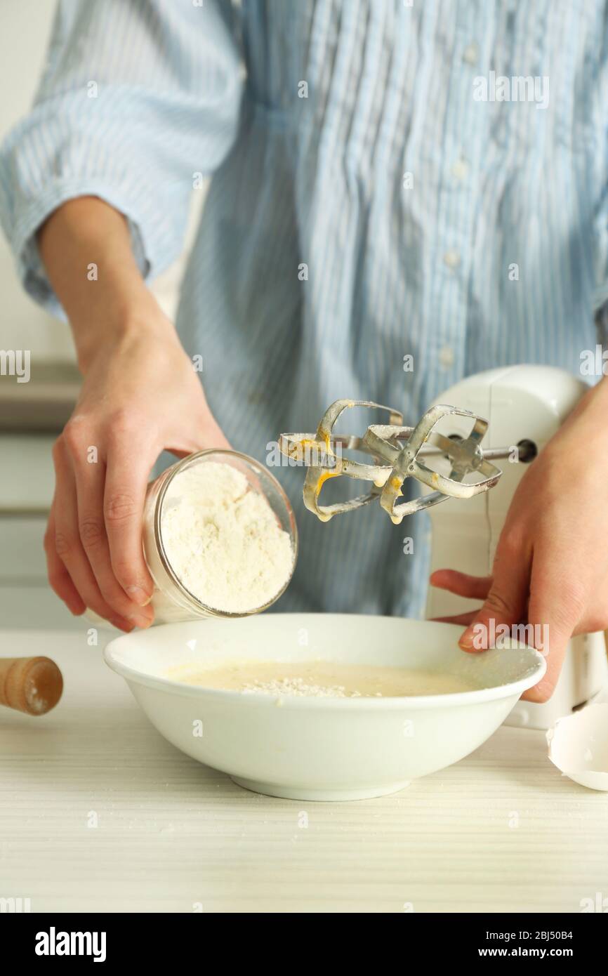 Woman is adding flour to the mixture Stock Photo - Alamy
