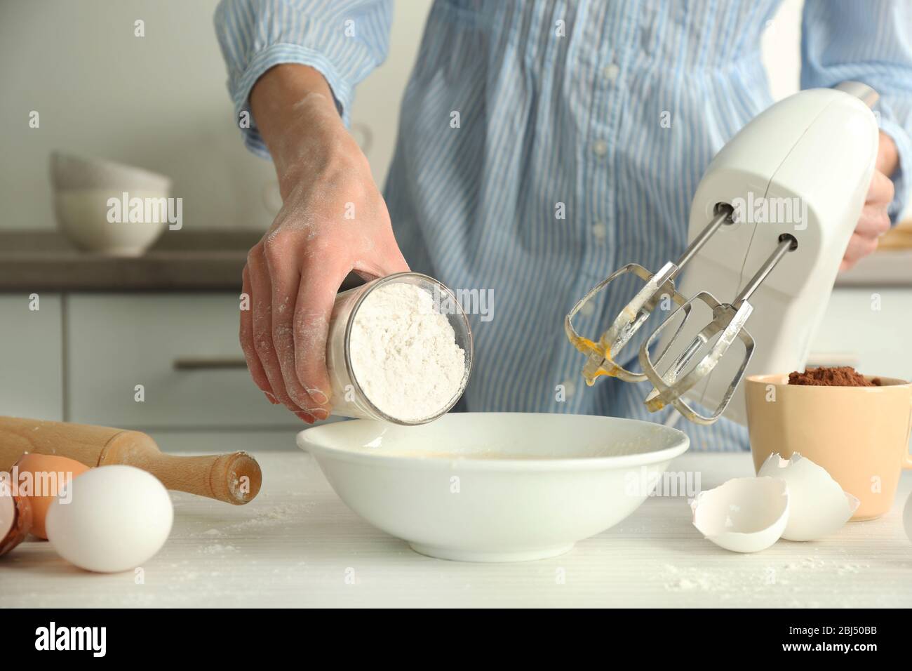 Woman is adding flour to the mixture Stock Photo - Alamy