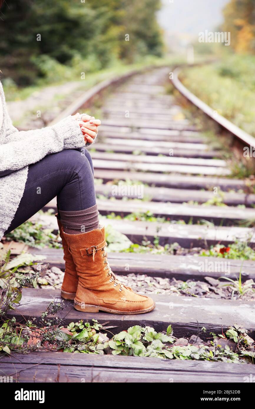 Young woman sitting on rail track Stock Photo - Alamy