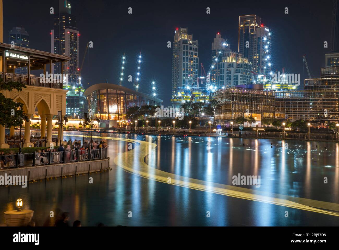 An illuminated Arabic abra boat passes by crowds of people awaiting the ...