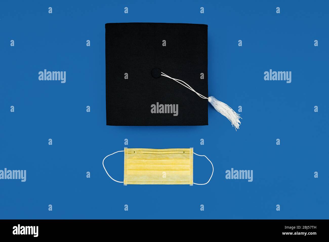 Graduation cap and face shield on blue isolated background Stock Photo ...