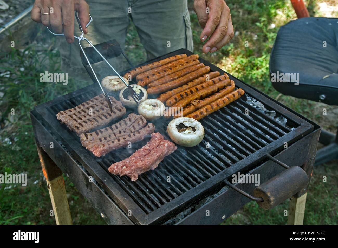 Preparing barbecue meat at picnic in nature. The meat is roasted in a ...
