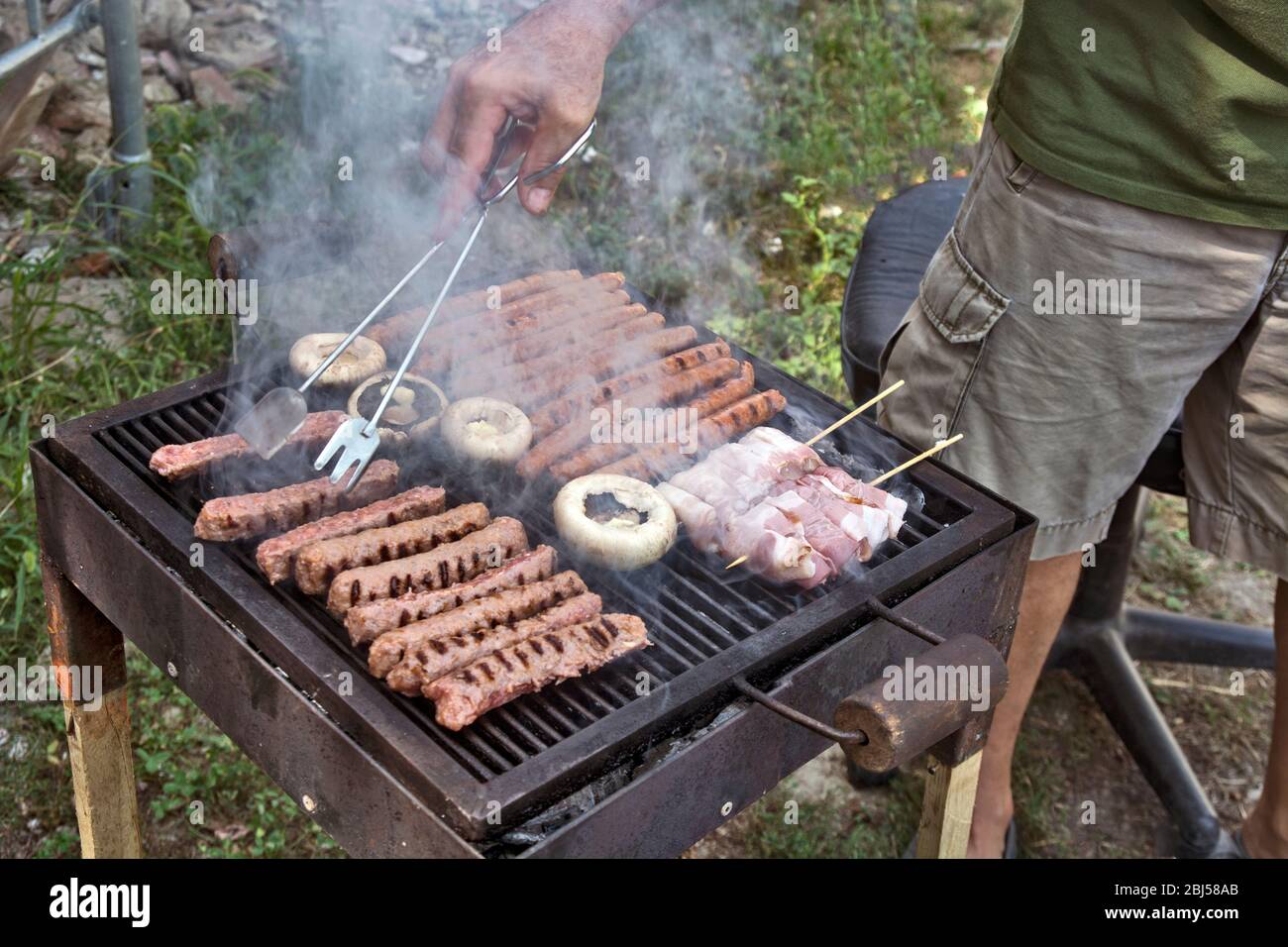 Preparing barbecue meat at picnic in nature. The meat is roasted in a ...
