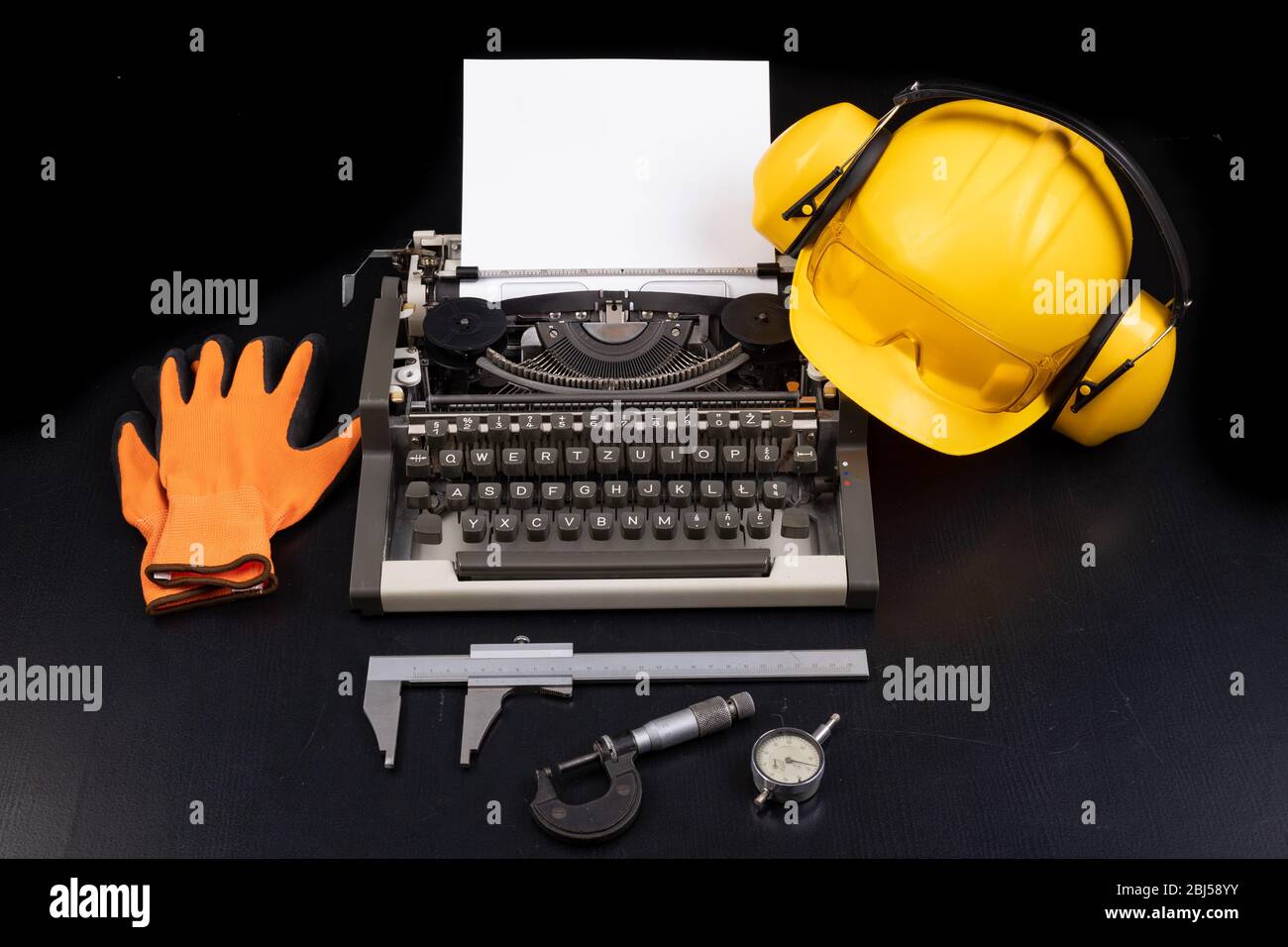 A construction helmet on an old typewriter. Measuring instruments used ...