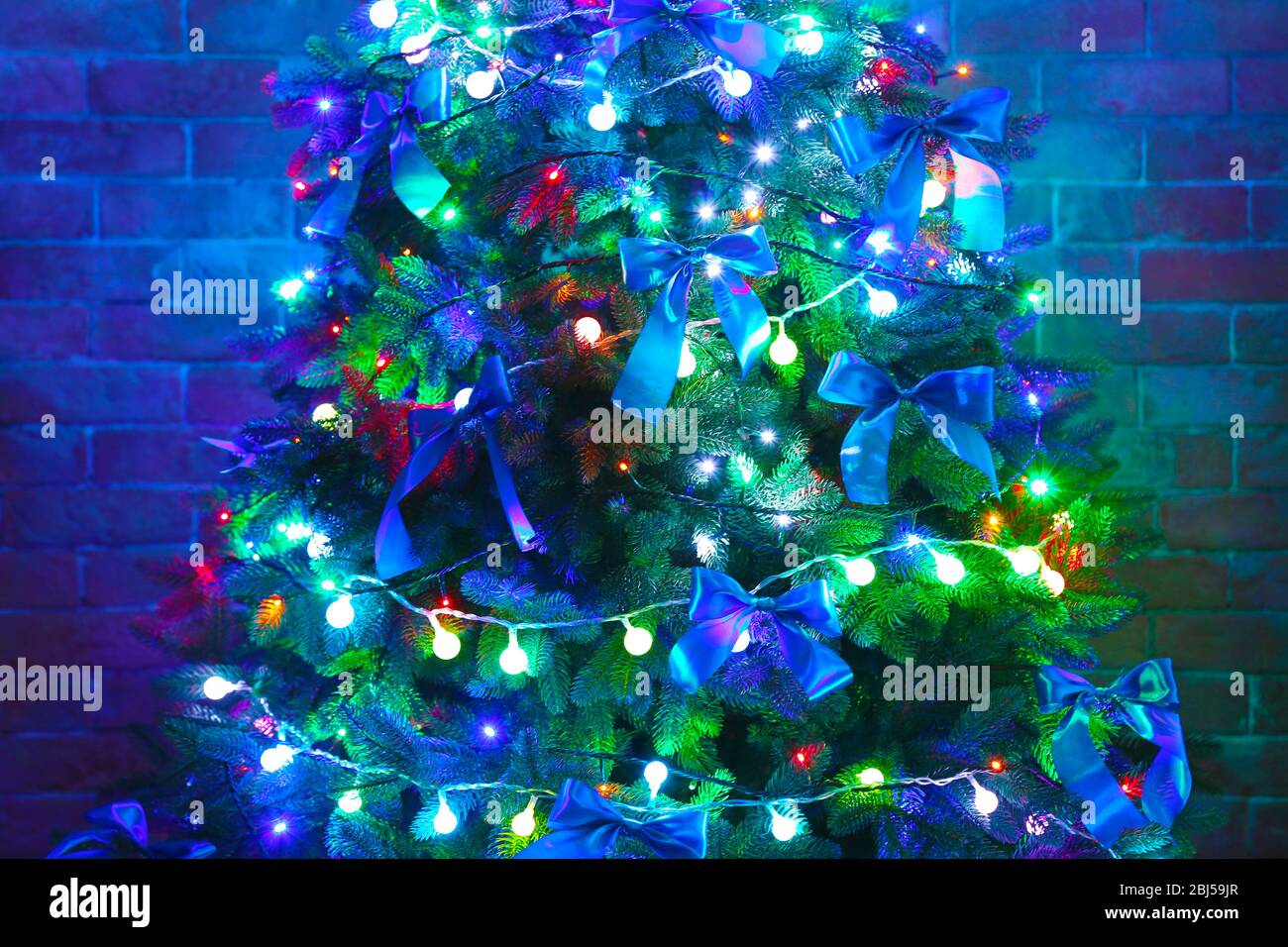 Christmas tree on brick wall background Stock Photo - Alamy