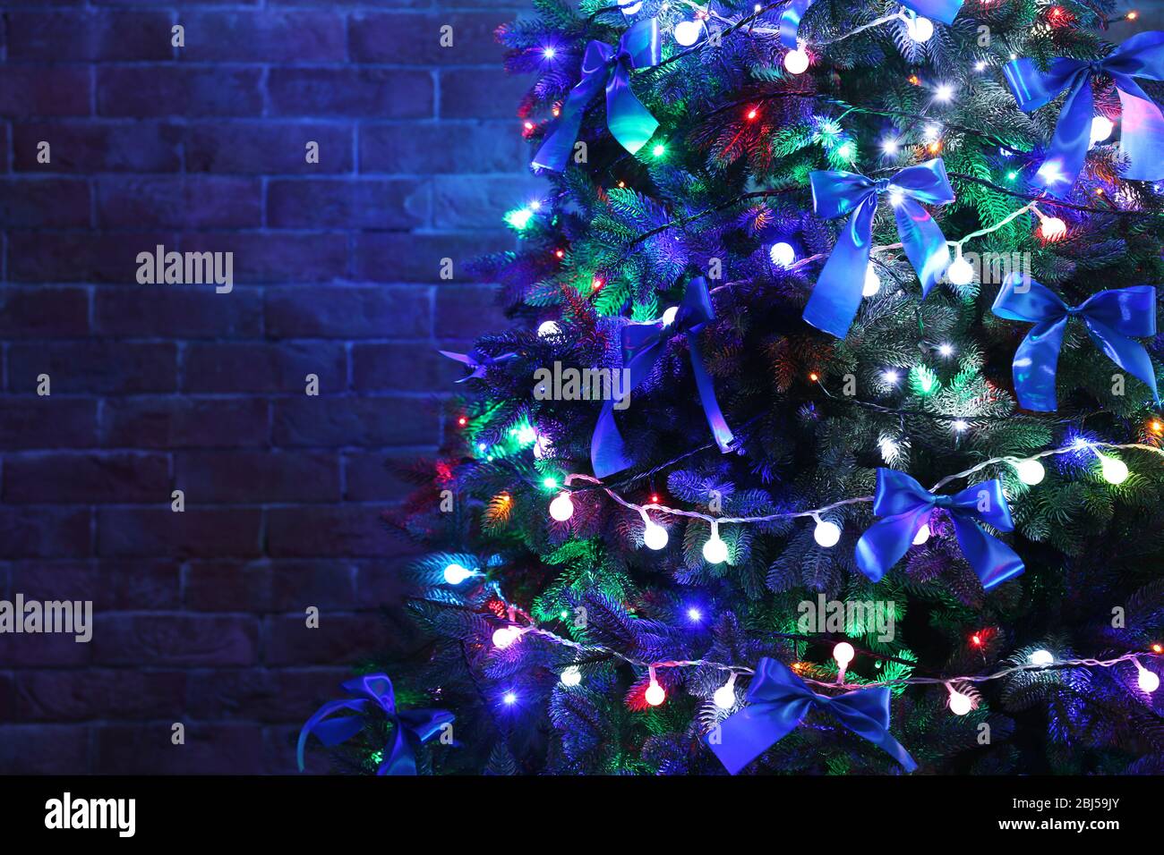 Christmas tree on brick wall background Stock Photo - Alamy