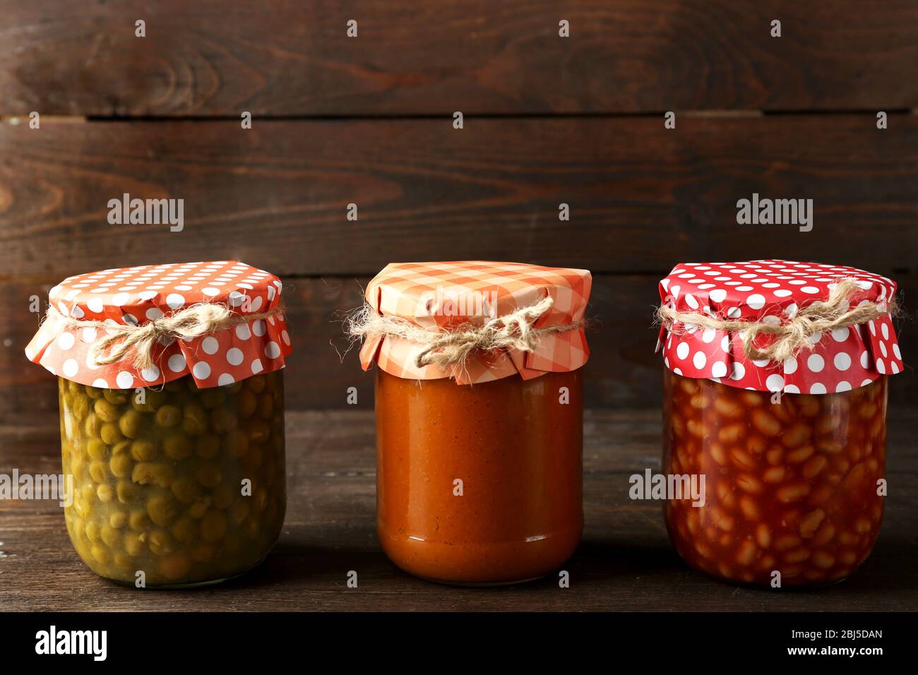 Jars with pickled vegetables and beans on wooden background Stock Photo ...