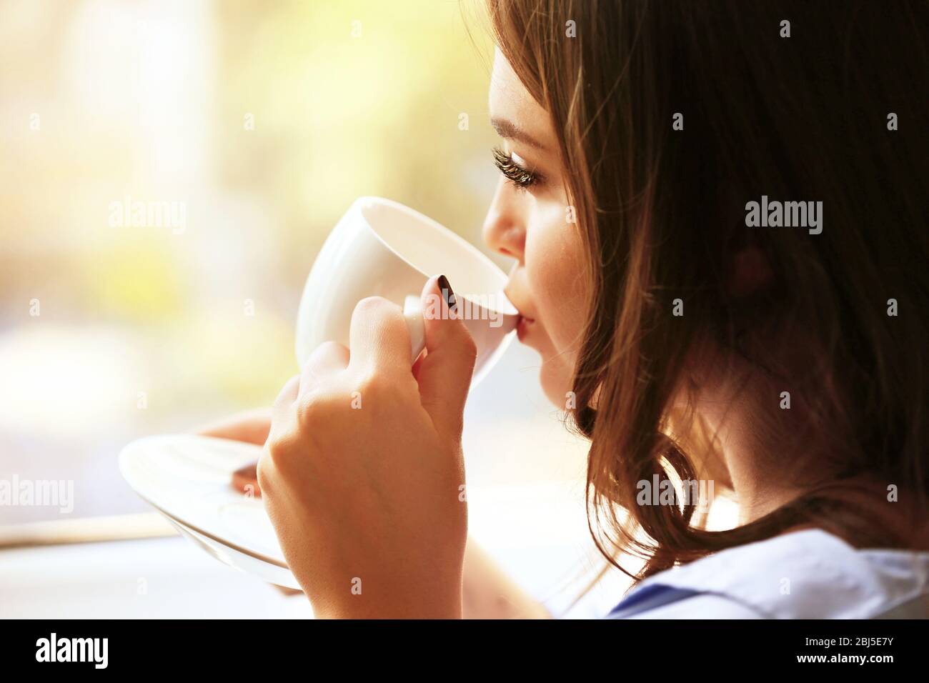 Woman drinking coffee near window in the room Stock Photo - Alamy
