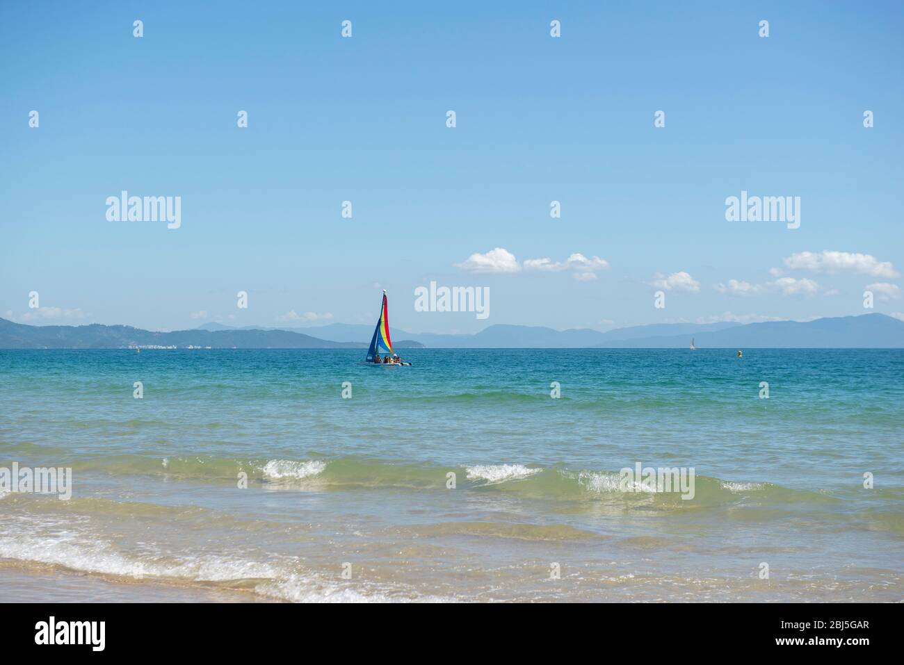 Small colorful catamaran sailboat in the blue sea. Sailing yacht ...