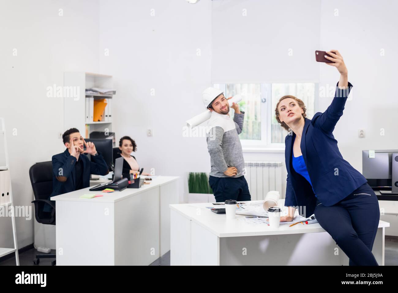 Employees having fun in the office, posing and taking selfies with a ...
