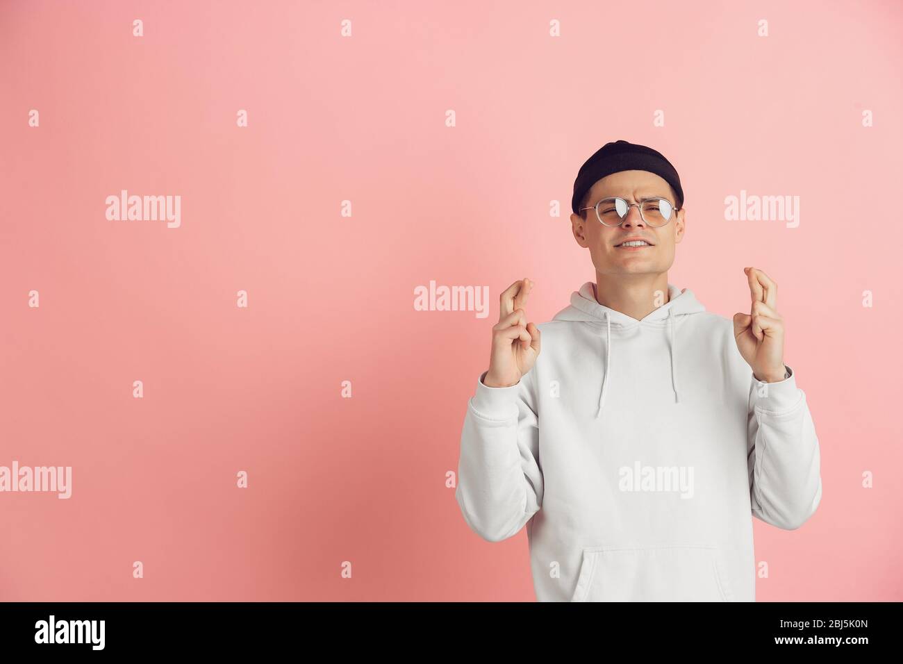 Praying for good luck. Caucasian young man's modern portrait isolated ...