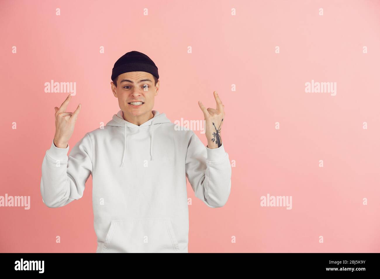 Rock horn gestures. Caucasian young man's modern portrait isolated on ...