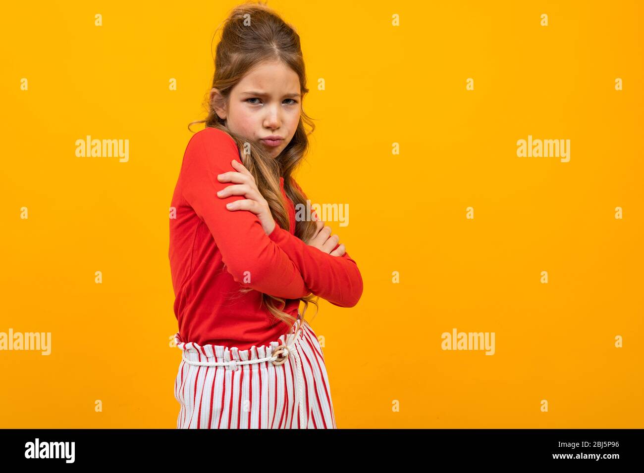 offended girl crossed her arms on a yellow background with copy space ...