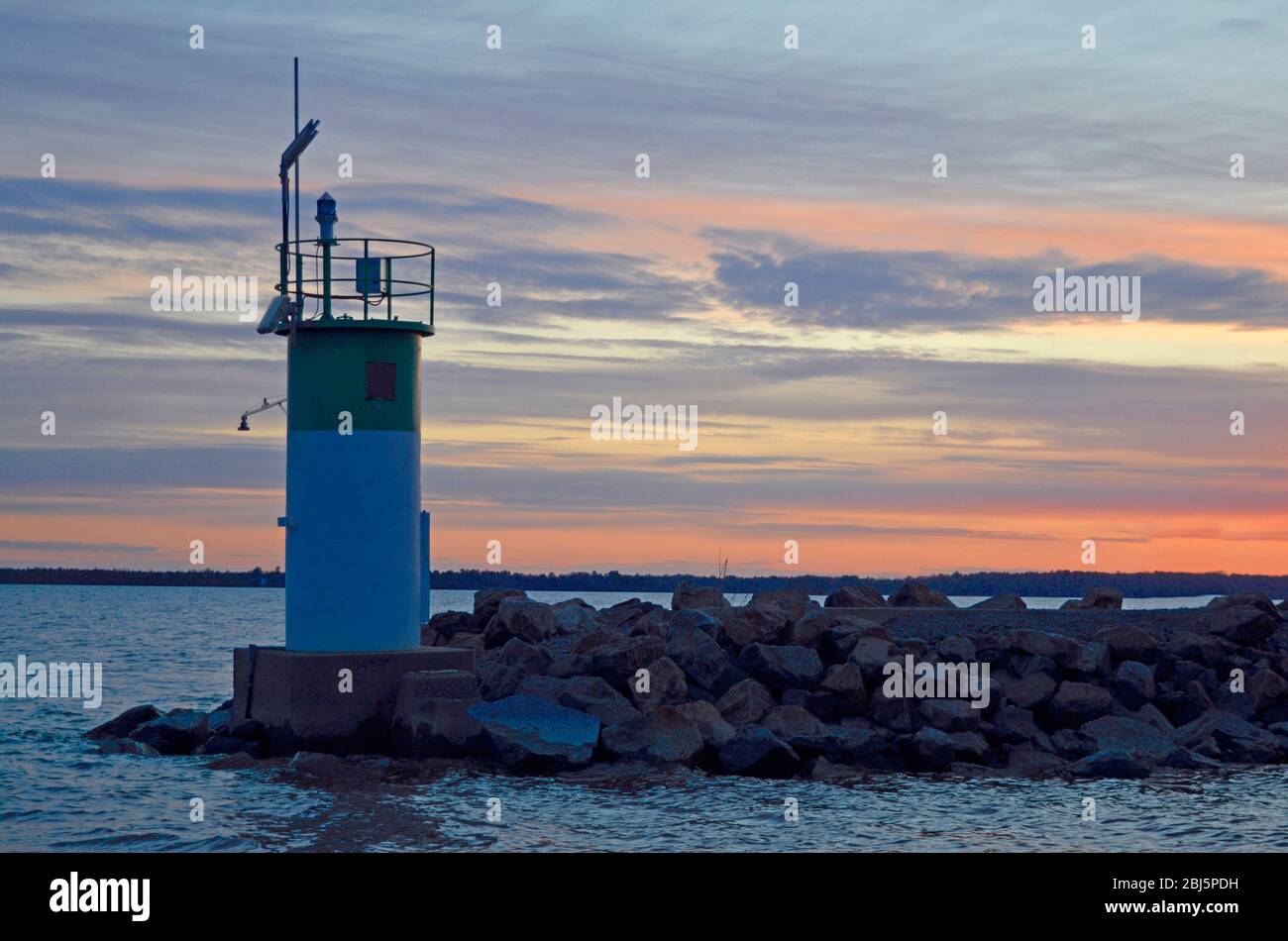 Lighthouse on the edge of a barrier marking the entrance to a marina ...