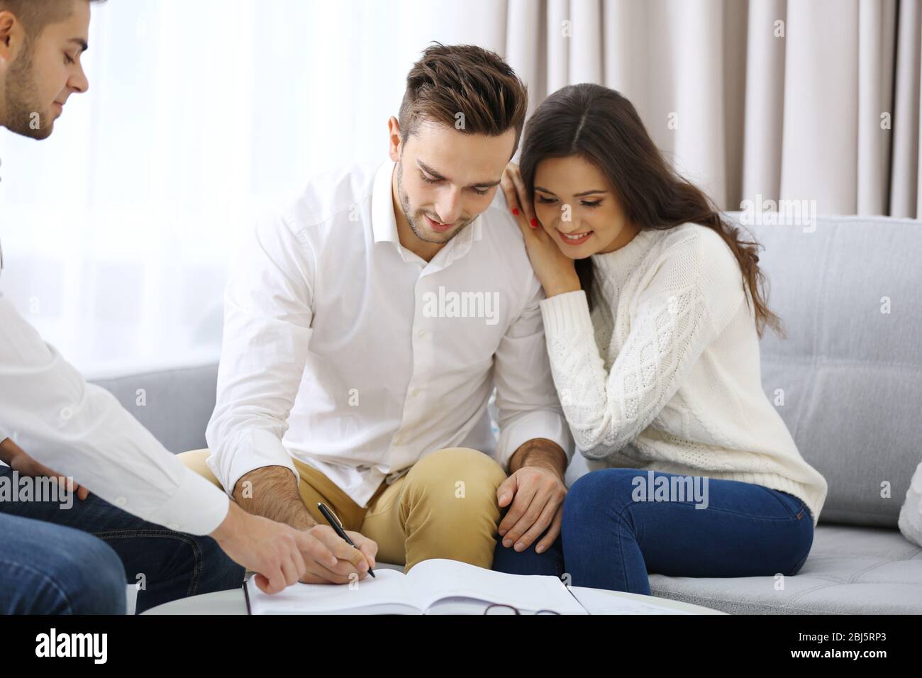 Estate agent meeting with happy couple, on light background Stock Photo ...