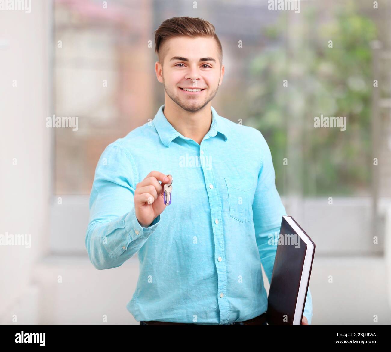Friendly male estate-agent on light background Stock Photo - Alamy