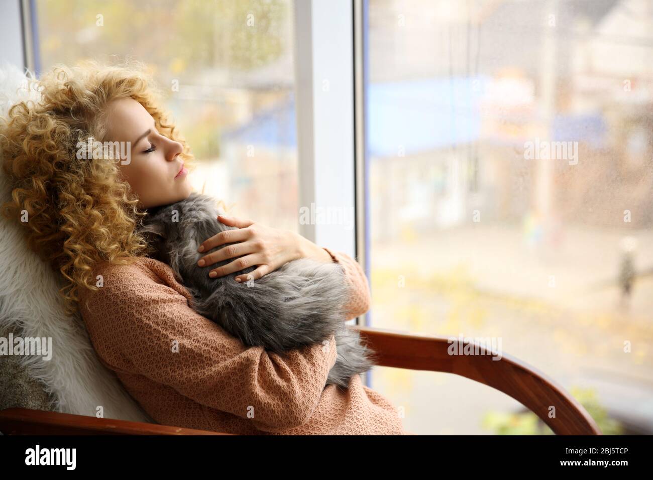Young woman and cat beside window in the room Stock Photo - Alamy