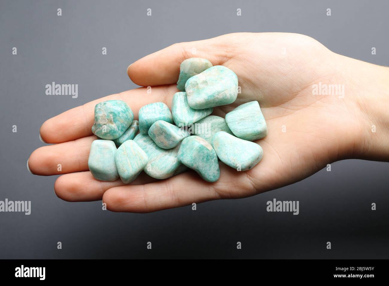 Woman holding semiprecious stones in her hand on dark grey background ...