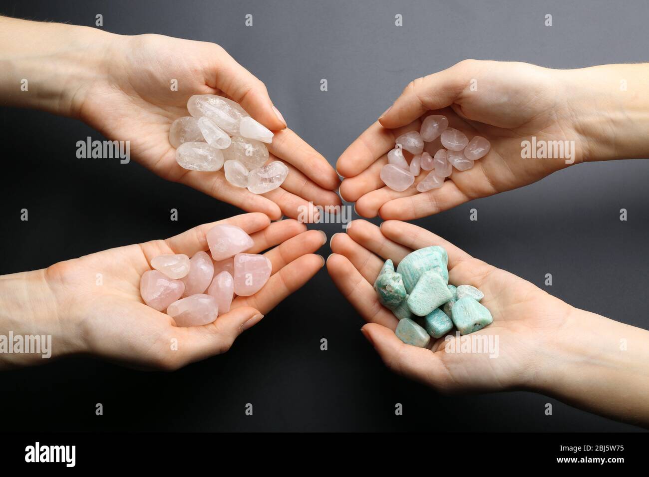Women holding semiprecious stones in their hands on dark grey ...