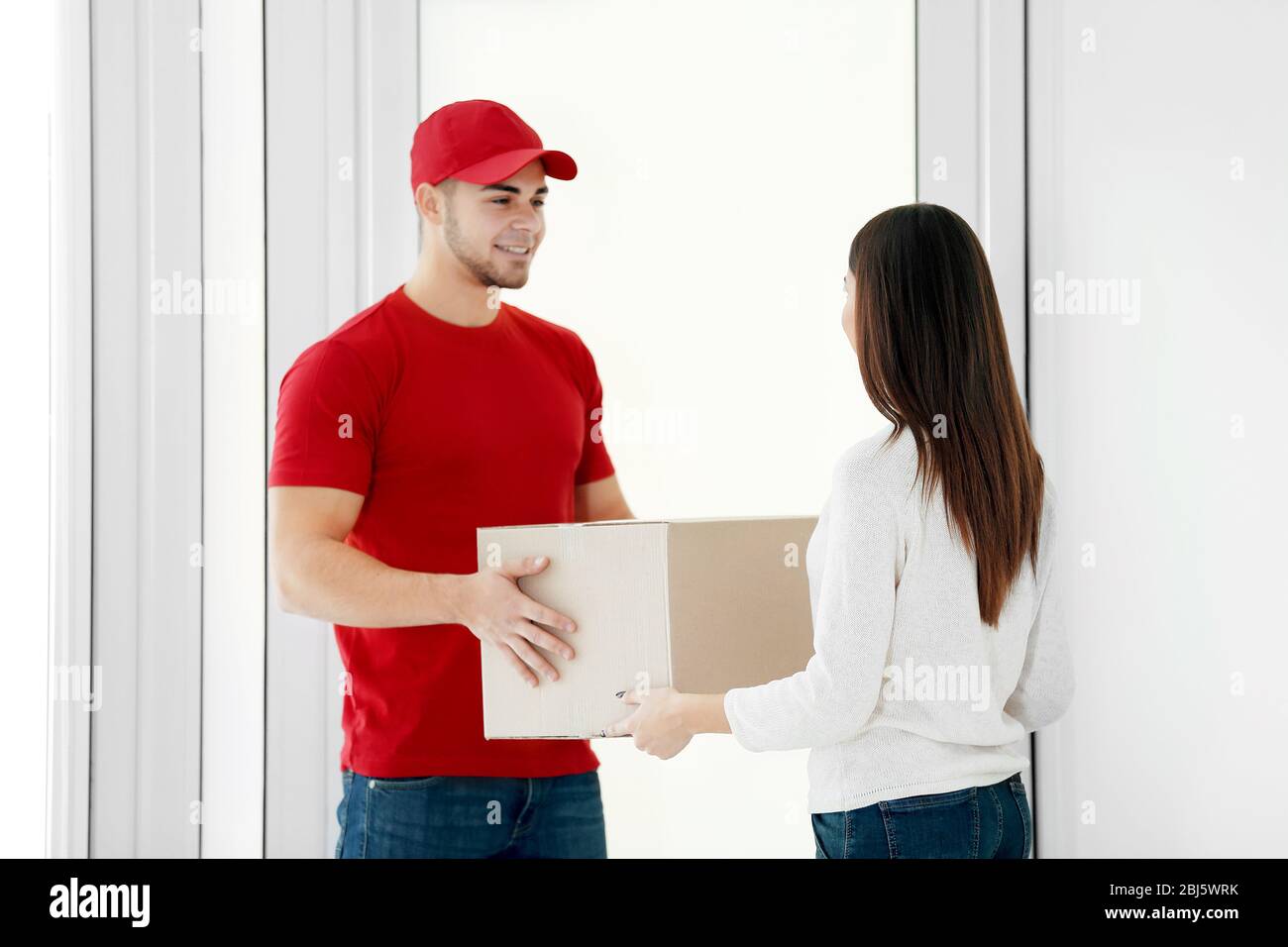 Young woman receiving parcel from delivery man Stock Photo - Alamy