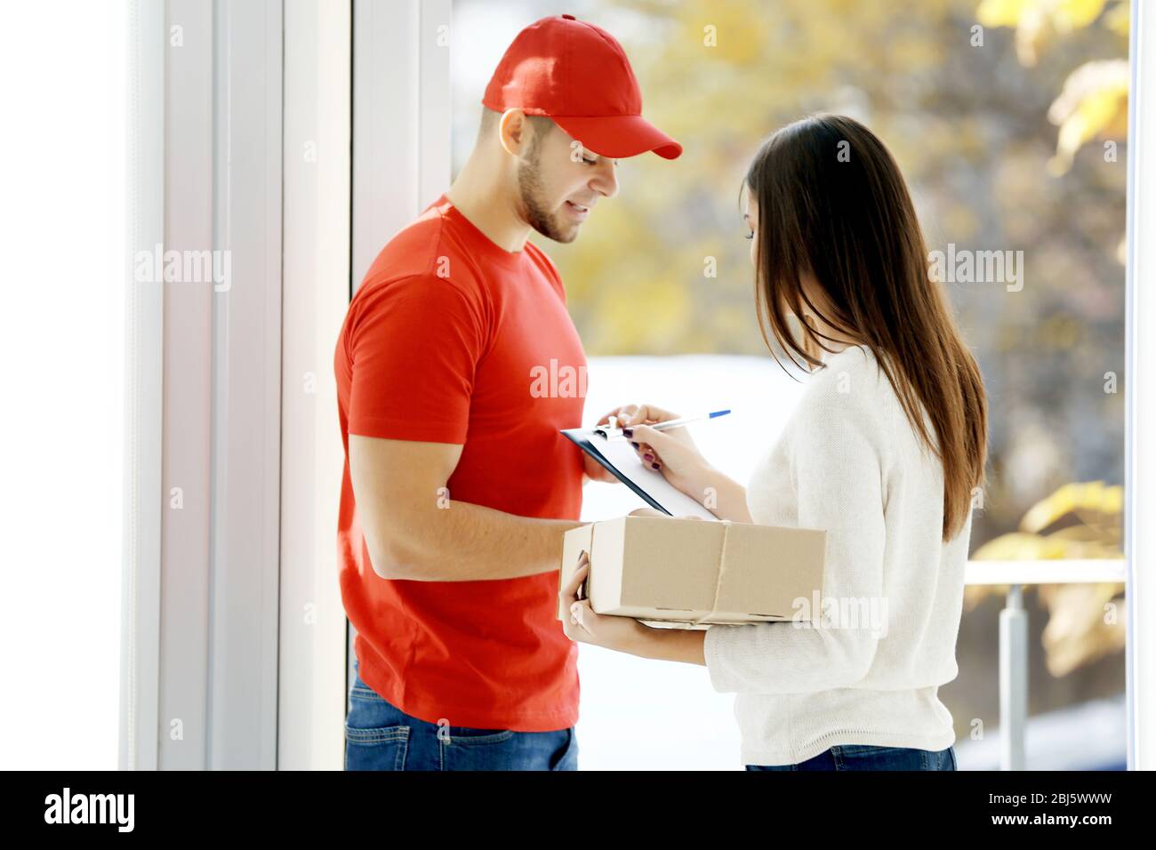 Young woman receiving parcel from delivery man Stock Photo - Alamy