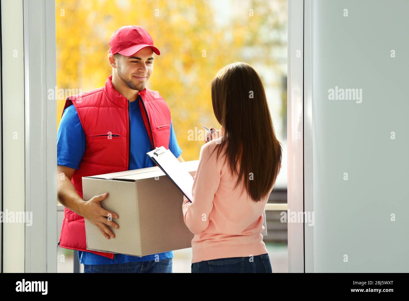 Young woman receiving parcel from delivery man Stock Photo - Alamy
