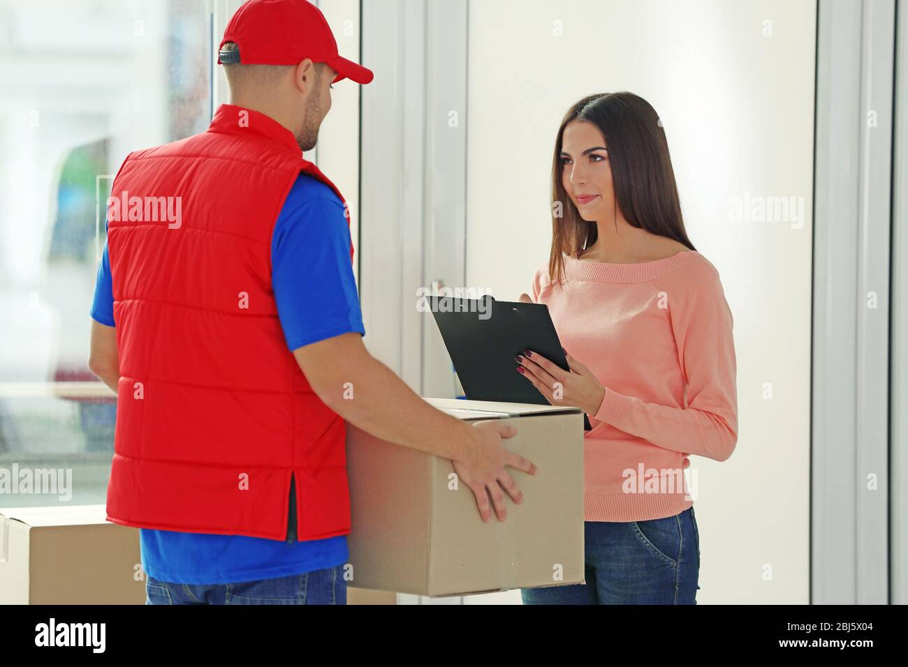 Receiving parcel - delivery man gives package to young woman Stock ...