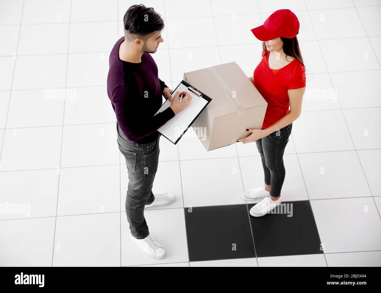Receiving parcel - delivery woman gives package to young man Stock ...