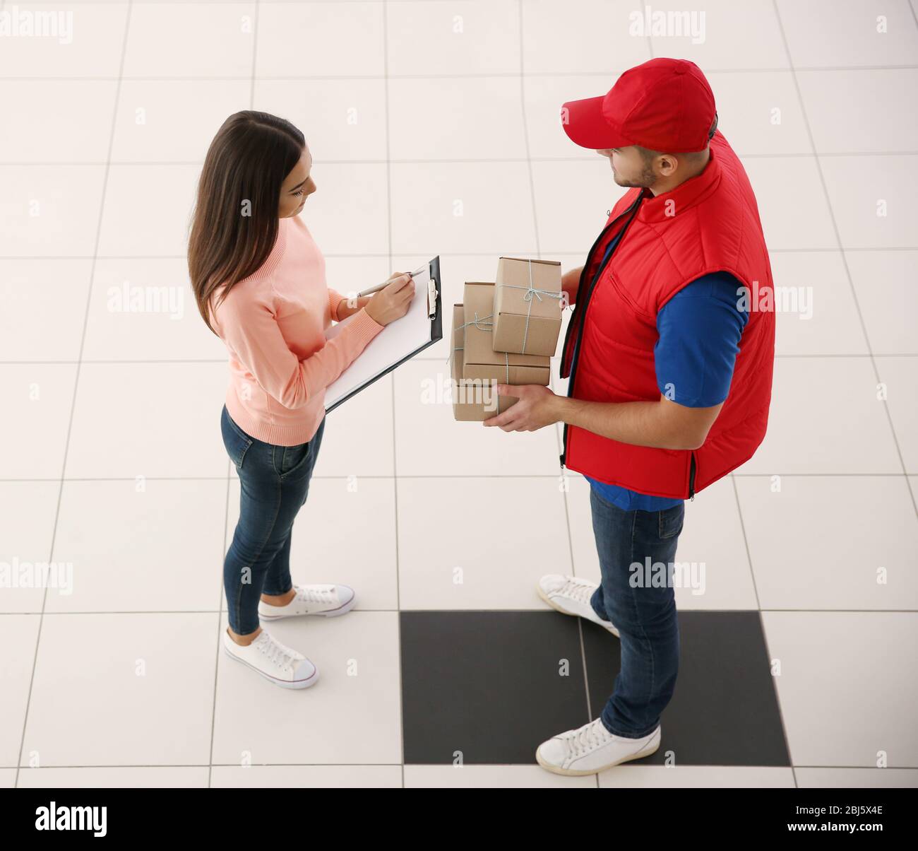 Receiving parcel - delivery man gives package to young woman Stock ...