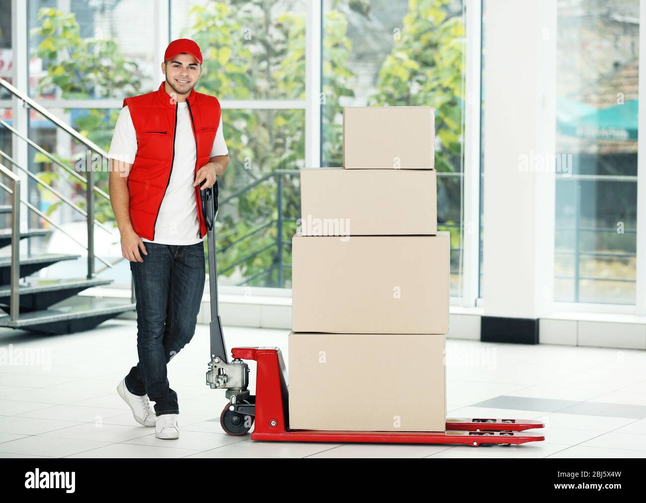 Delivery concept - postman in red uniform with parcels on dolly Stock ...