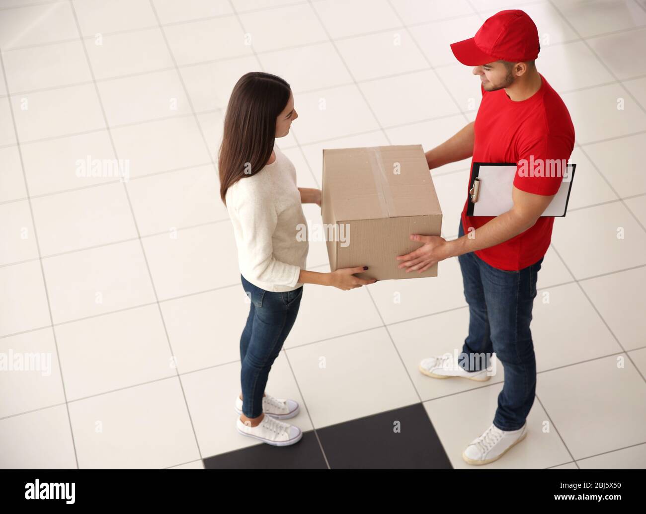 Receiving parcel - delivery man gives package to young woman Stock ...